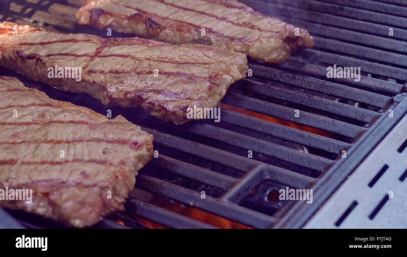 Step by step. Grilling New York strip steak on outdoor gas grill Stock ...
