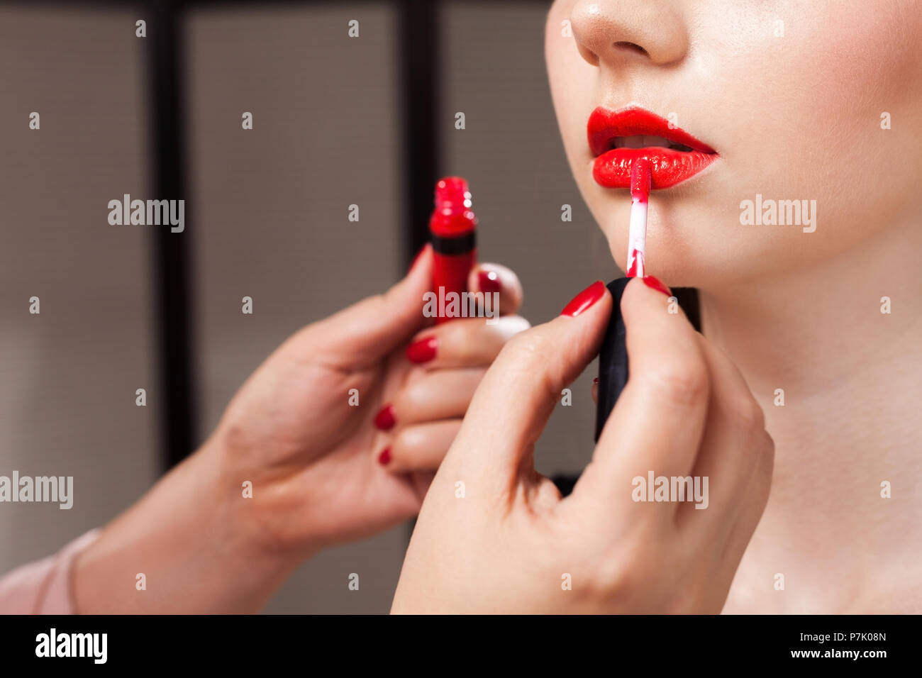 makeup woman putting red lip gloss on a client close up Stock Photo - Alamy