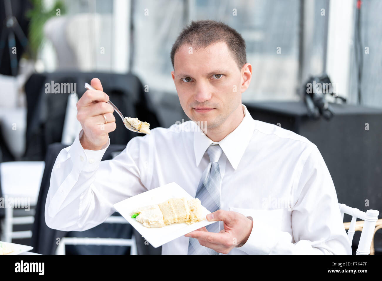 Young guilty unsure man in business formal dress shirt eating cake ...