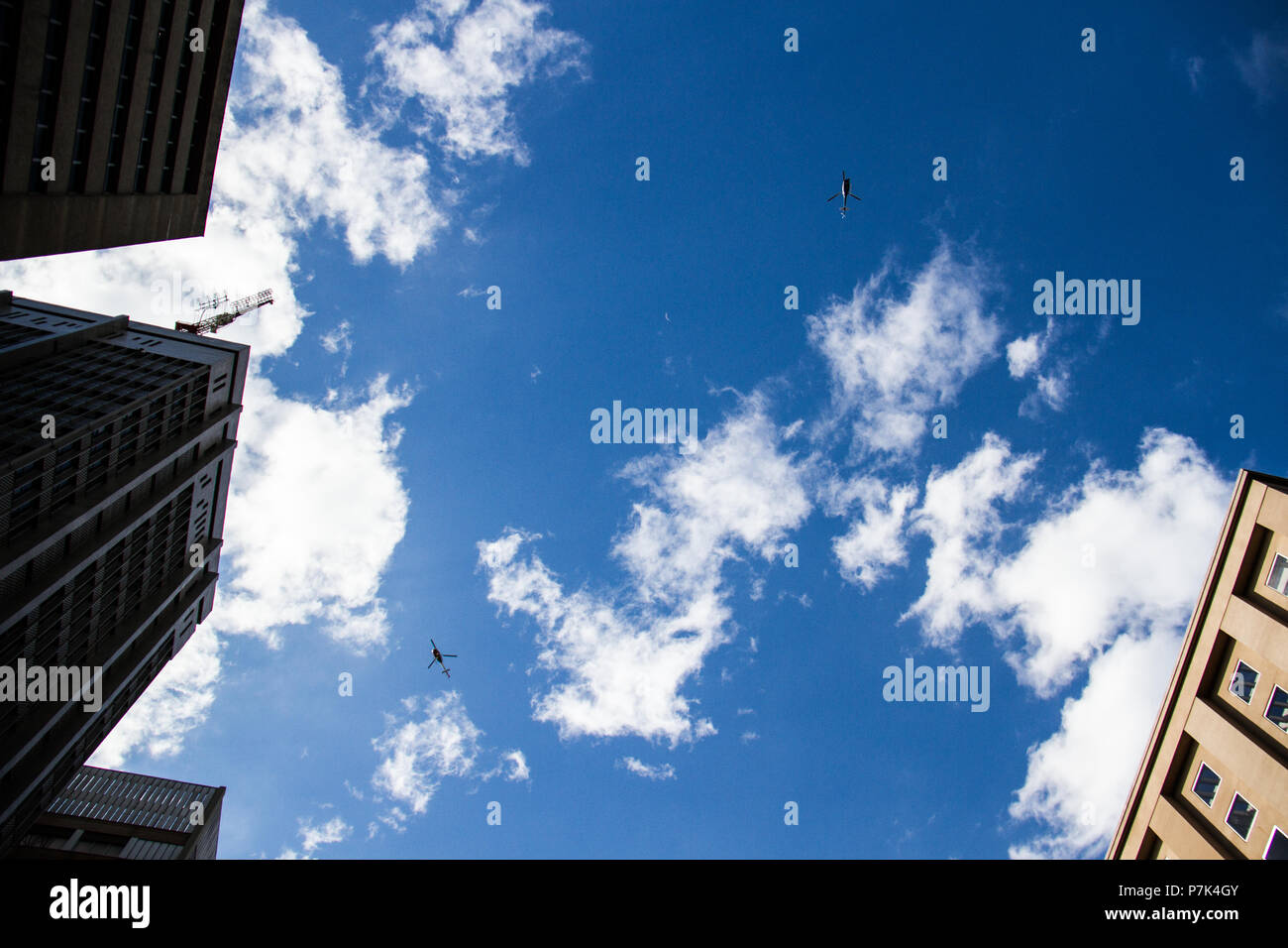 Low angle view of helicopters flying in a blue sky with clouds on top ...