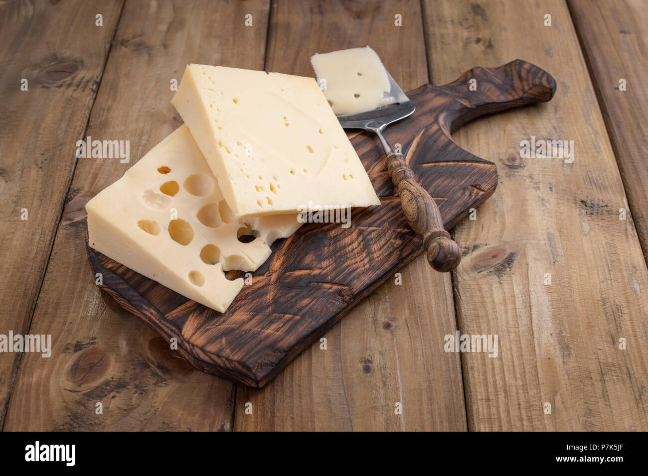 Traditional Dutch cheese with holes, on a vintage wooden board, wooden ...