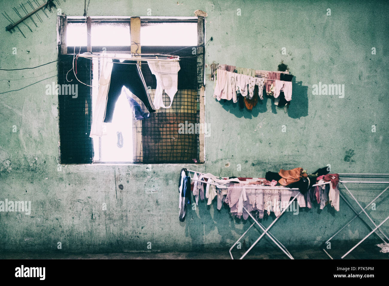 Cracked walls and floor with drying clothes near a window of a decayed ...