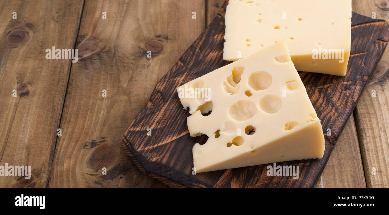 Traditional Dutch cheese with holes, on a vintage wooden board, wooden ...