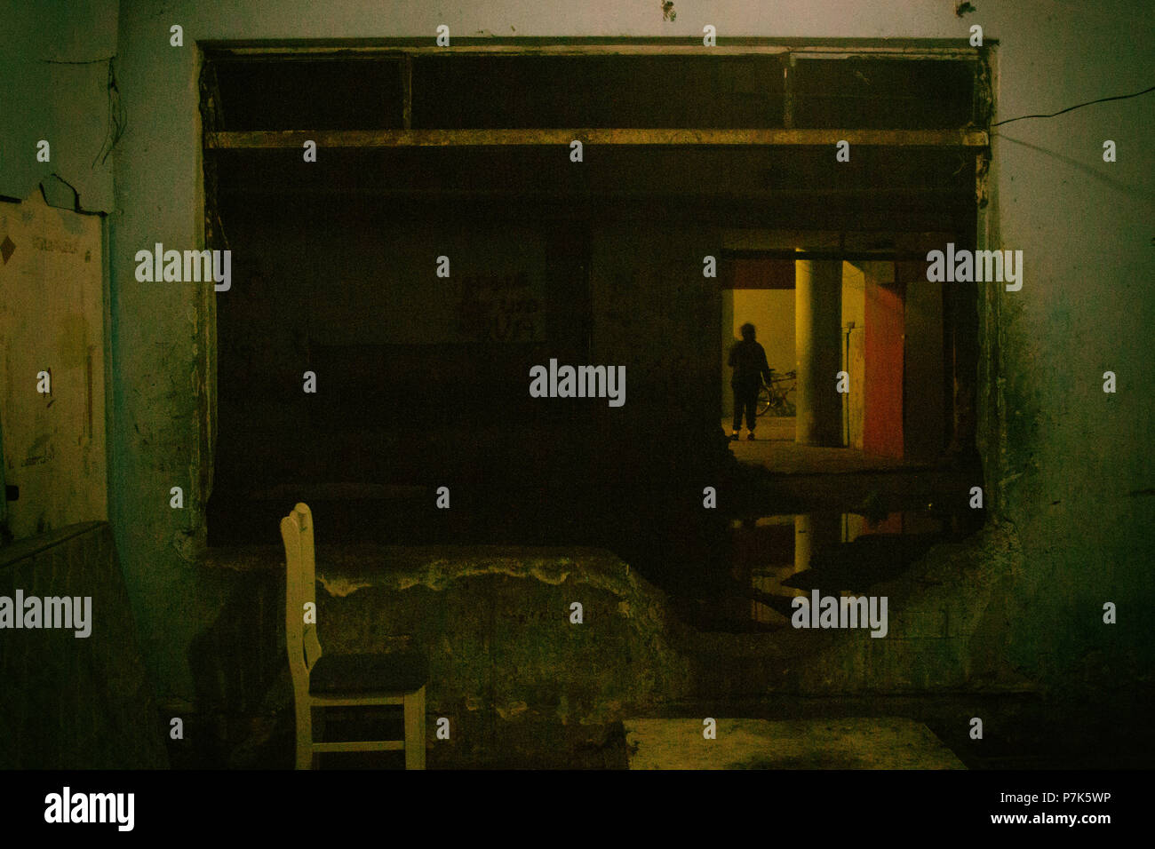 White wood chair in front of a hole in shabby wall used as passage in a ...