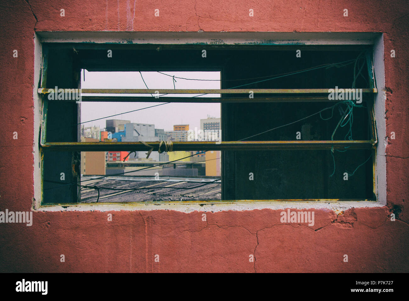 Ruined window with warn blinds with no glass and shabby red walls. City ...