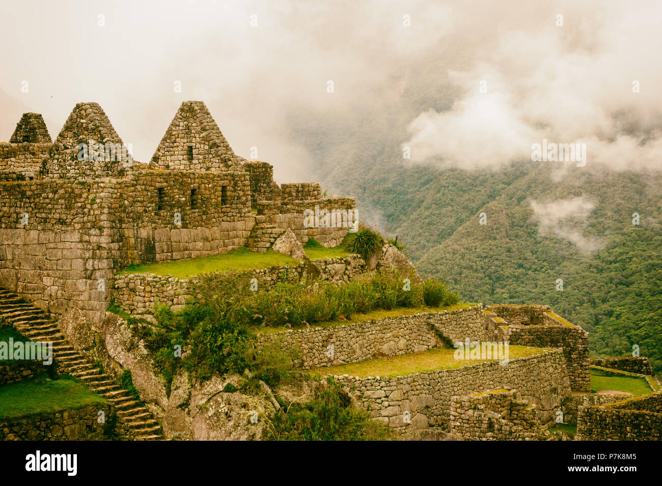 Ruins of houses and farming terraces on a cliff at Machu Picchu. Peru ...