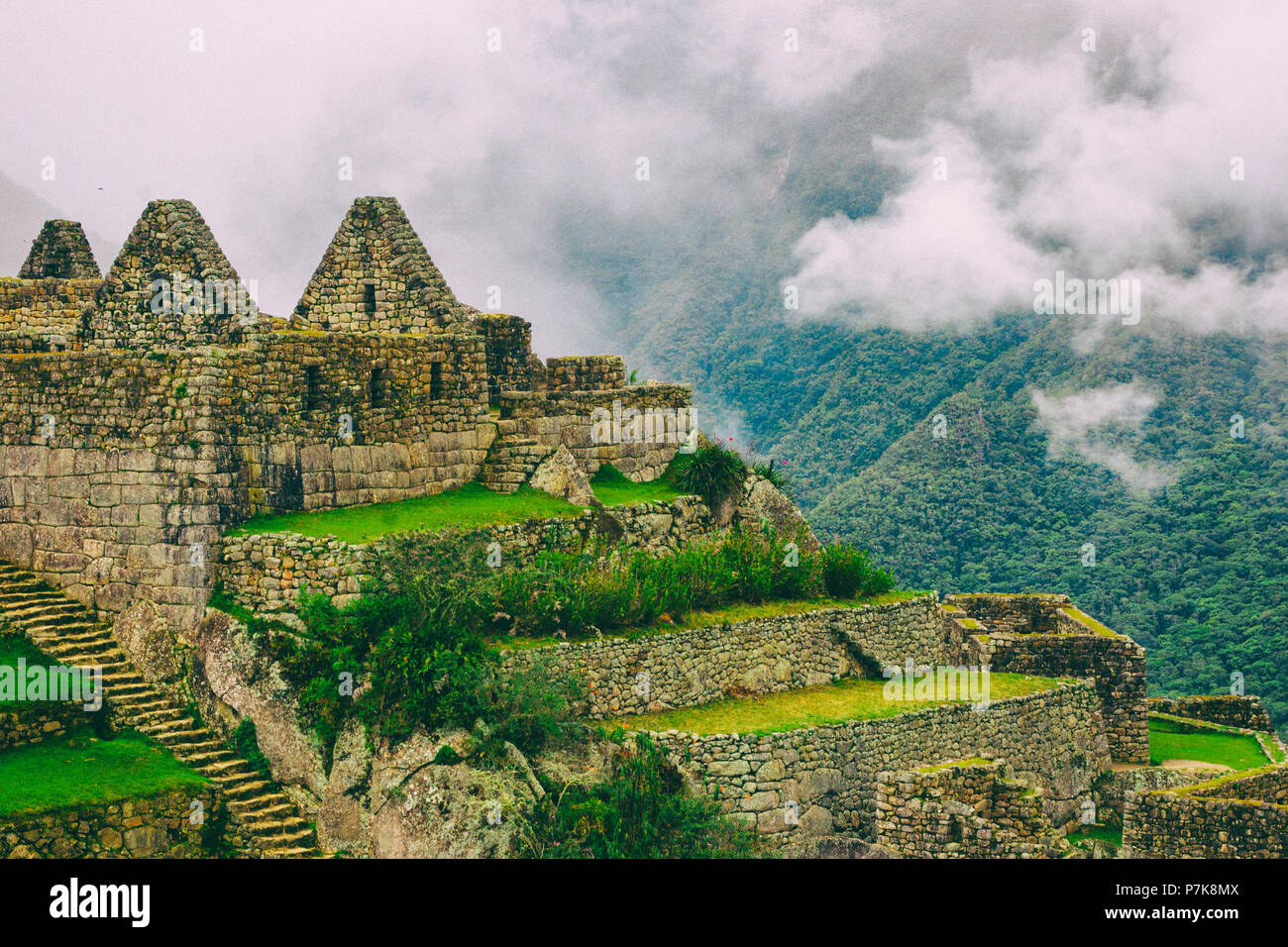 Ruins of houses and farming terraces on a cliff at Machu Picchu. Peru ...