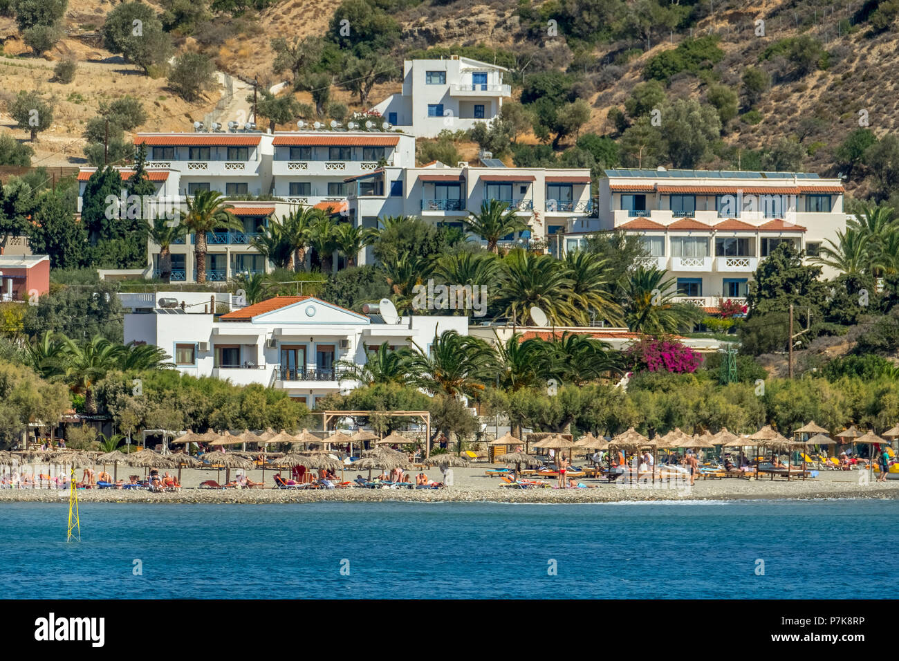 Sandy beach with bathers of Agia Galini in front of hotels, pebble ...