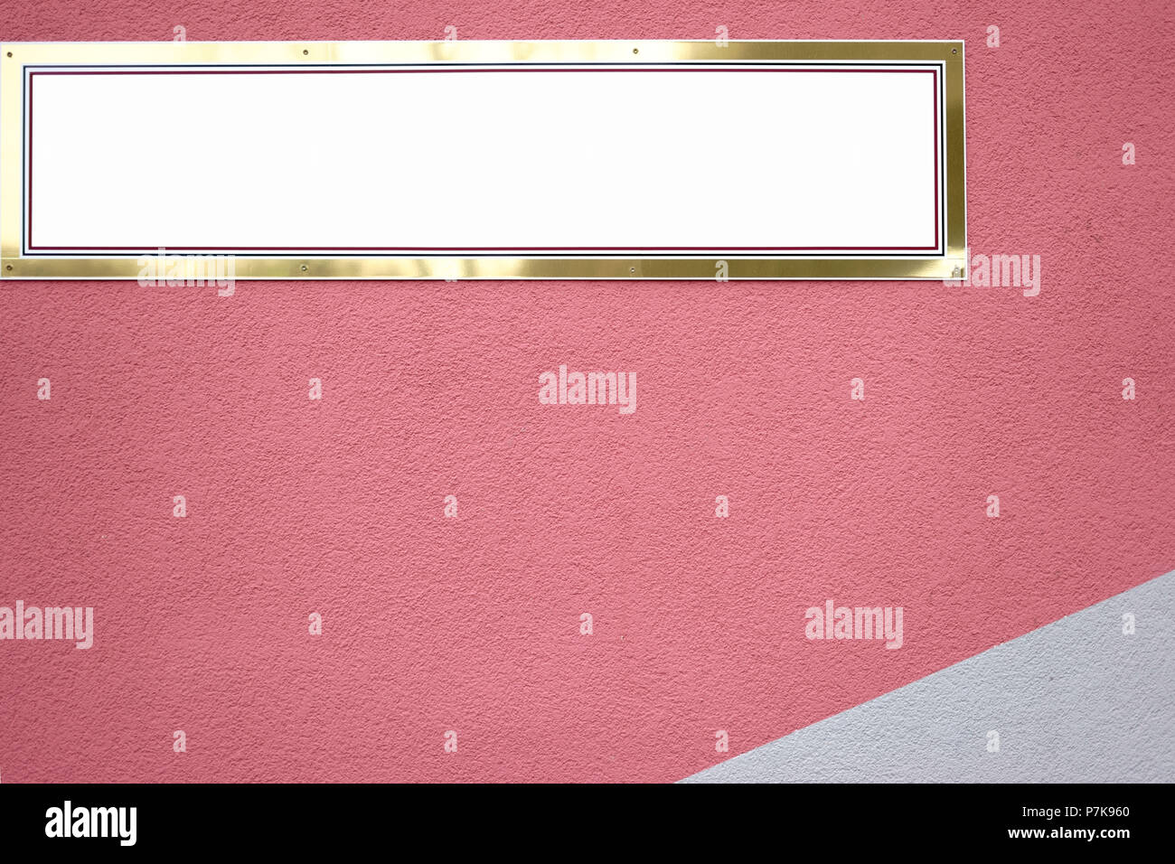 An empty sign with a gold frame on a two-tone modern facade of a ...