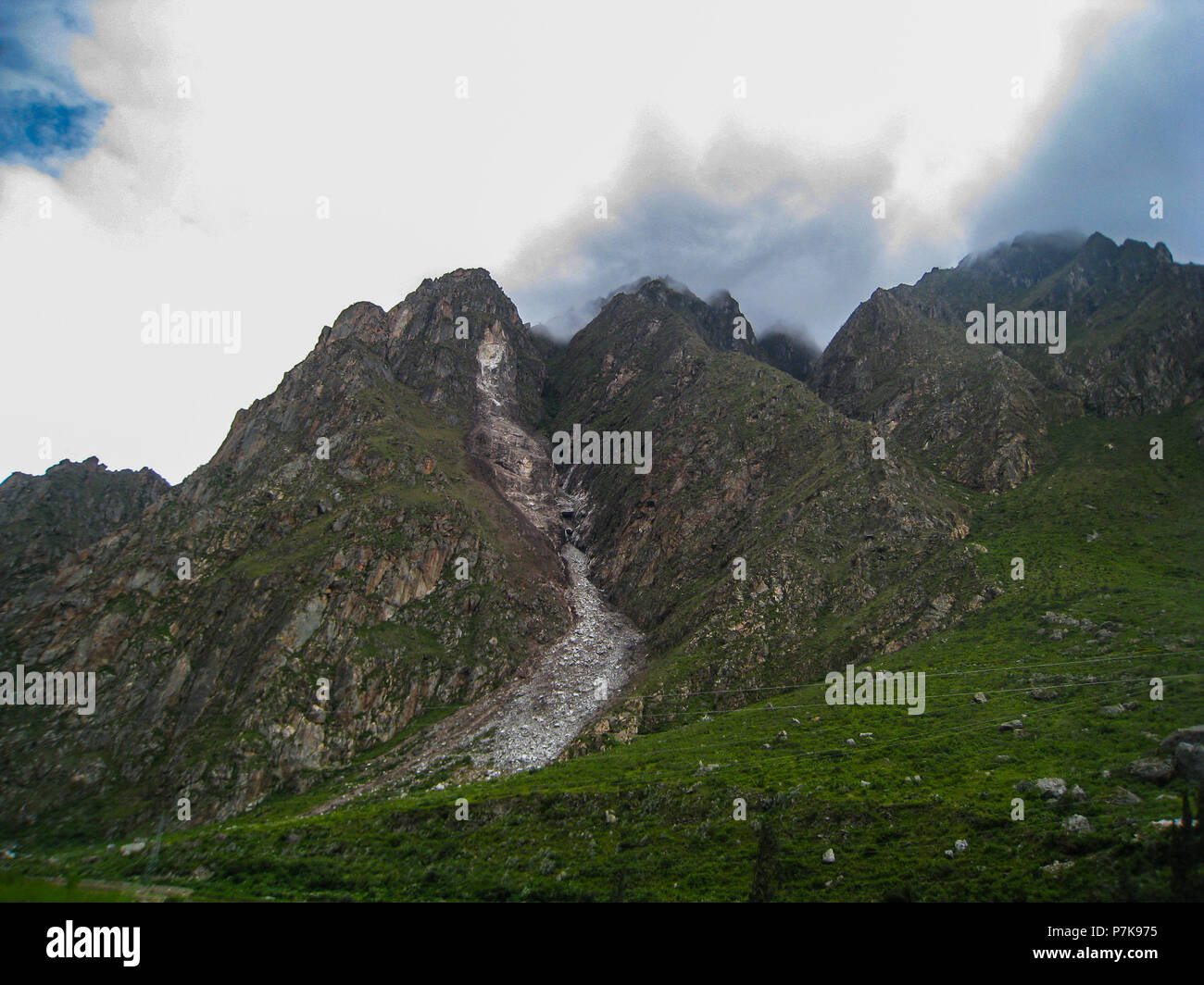 Mountain split by falling stones in the Andes. Green grass and white ...