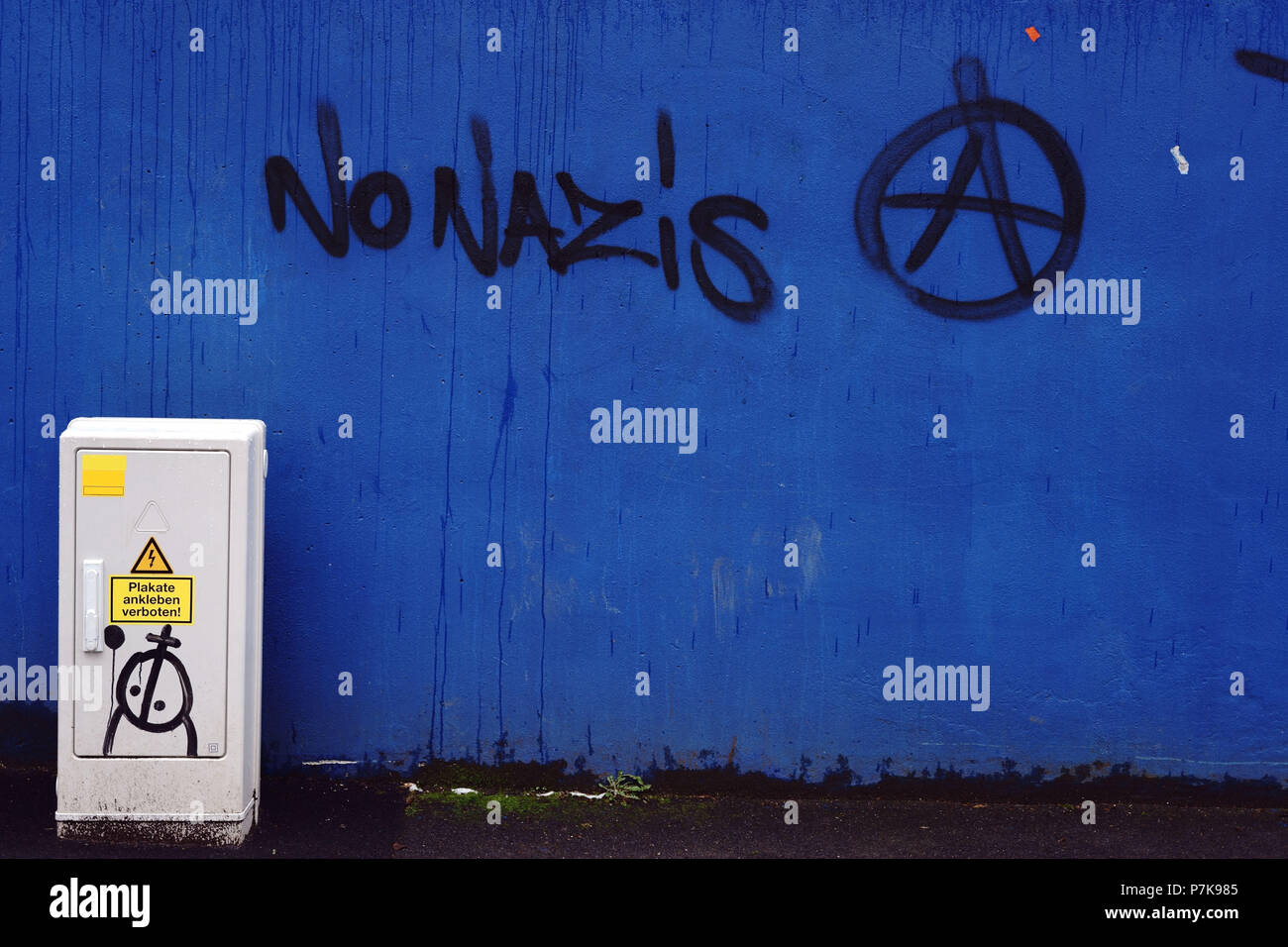 The political slogan 'No Nazis' on a blue wall with a power ...