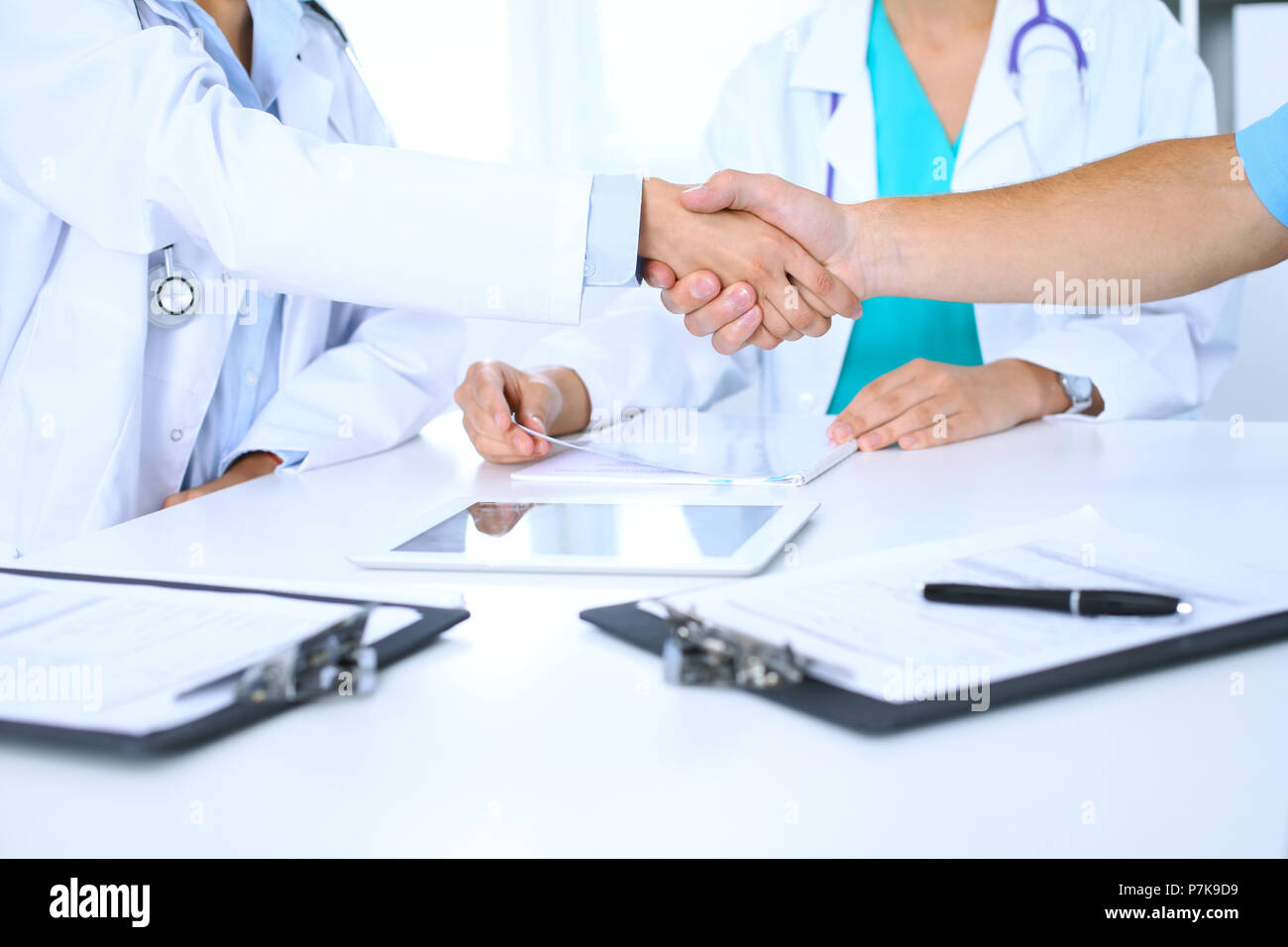 Two doctors shaking hands to each other at meeting. Teamwork and ...
