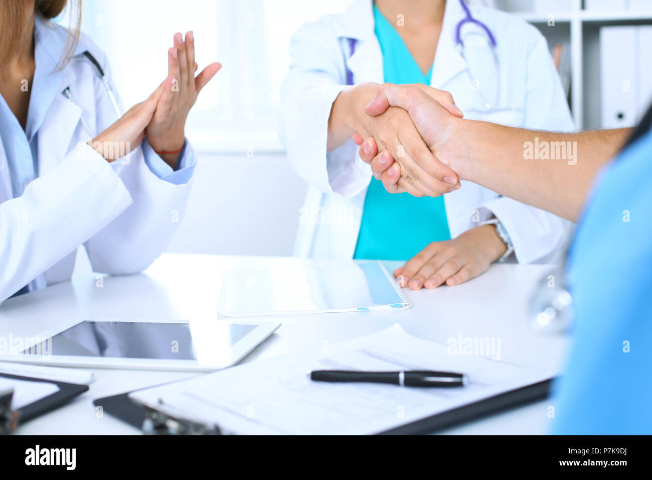 Two doctors shaking hands to each other at meeting. Teamwork and ...