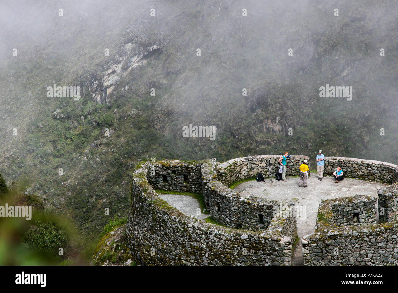 Hikers of the Inca Trail on a Inca ruin on a cliff in the mountains ...