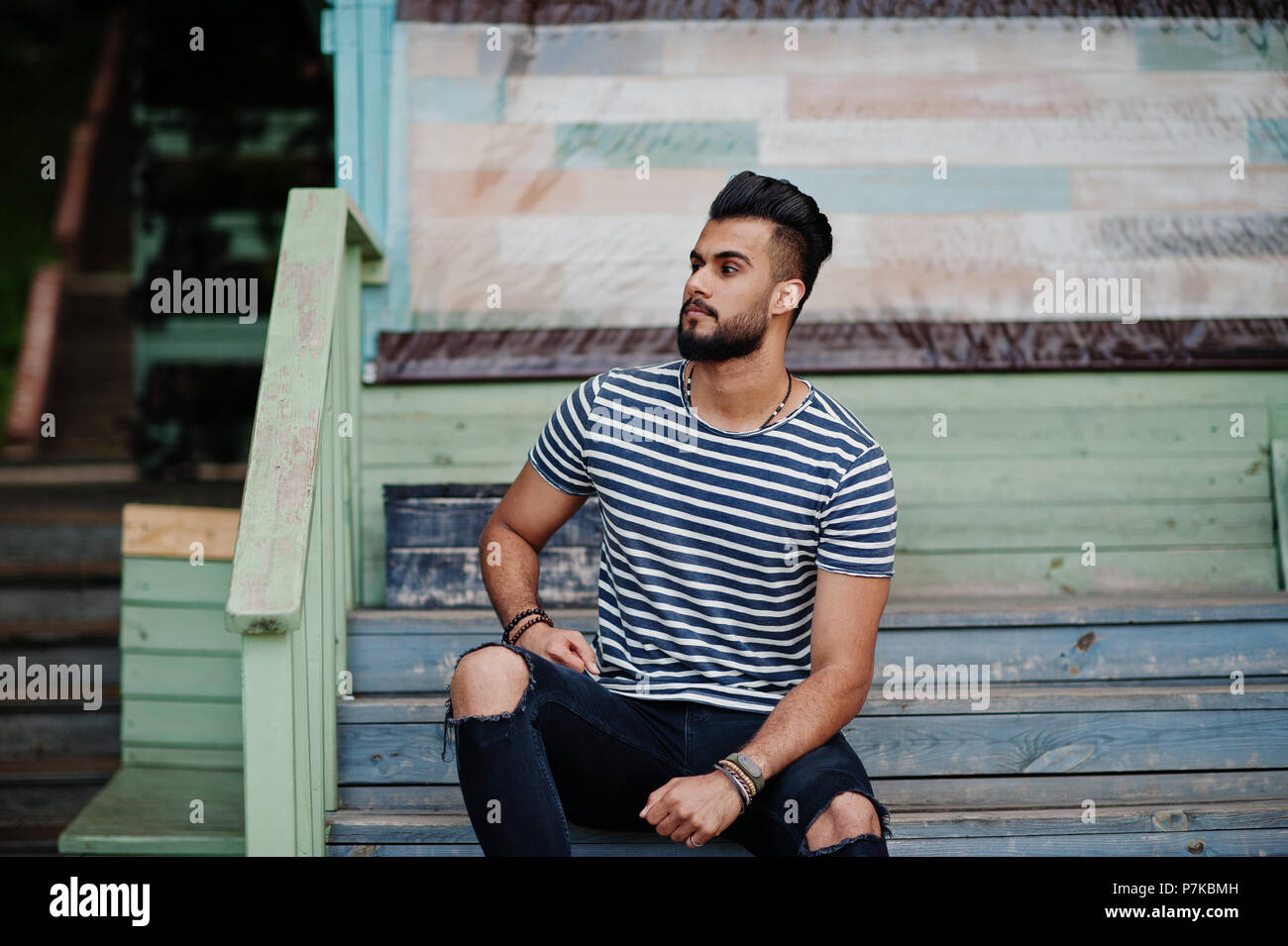 Handsome tall arabian beard man model at stripped shirt posed outdoor ...
