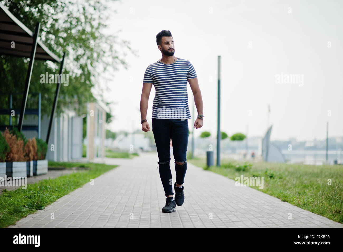 Handsome tall arabian beard man model at stripped shirt posed outdoor ...