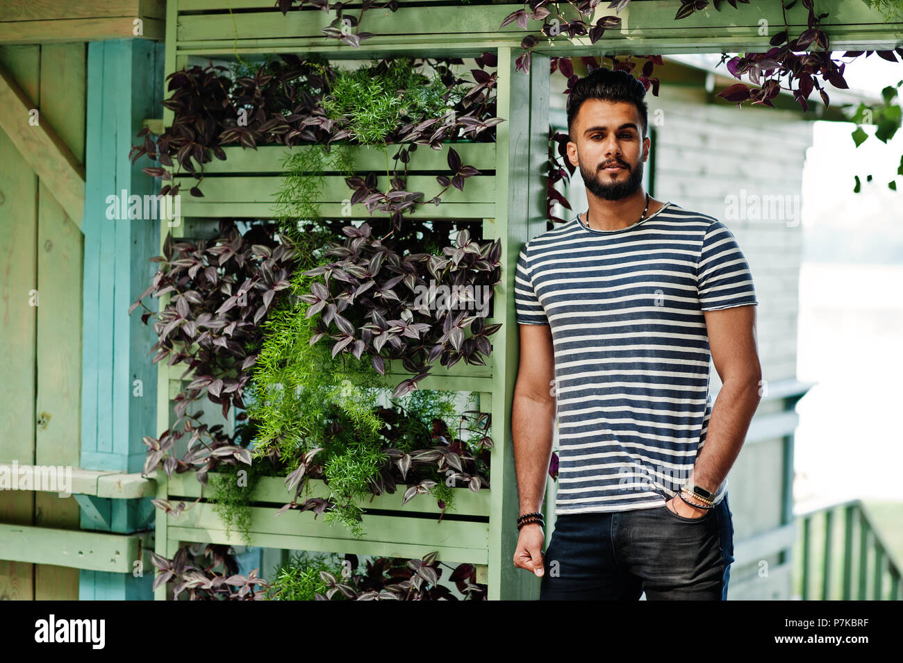 Handsome tall arabian beard man model at stripped shirt posed outdoor ...