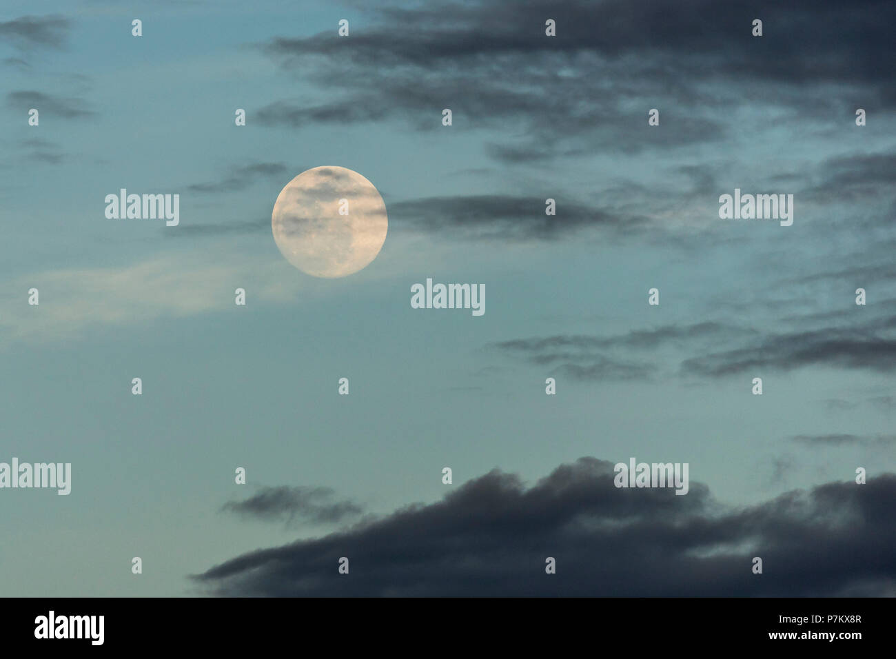 Full moon between clouds Stock Photo - Alamy