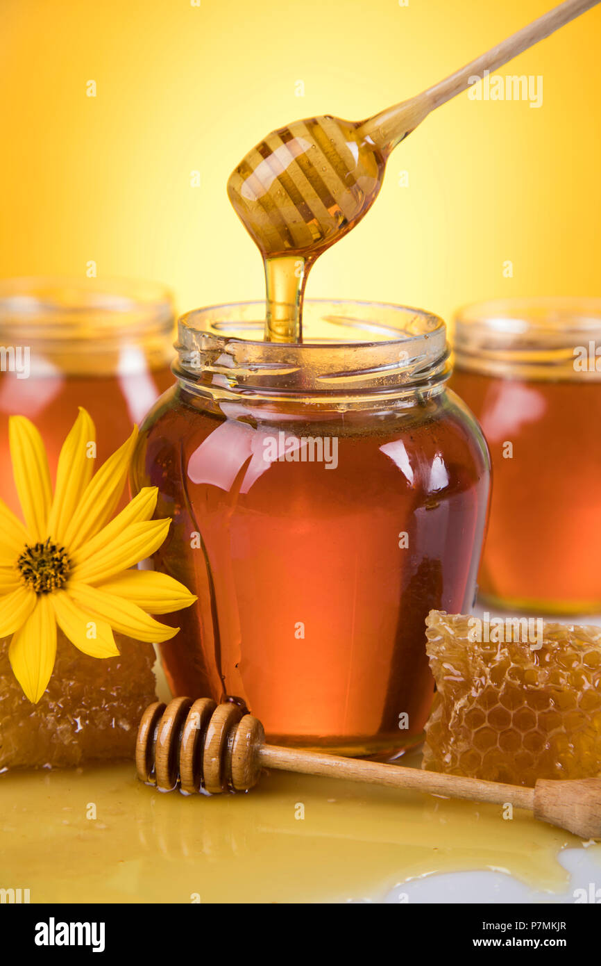 Honey jar, flower with dipper and flowing honey Stock Photo - Alamy