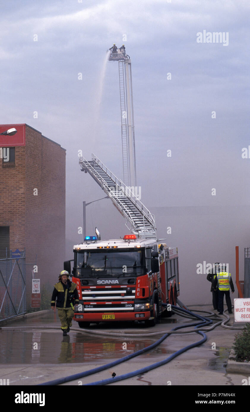 Firemen and fire engine at a factory fire in an inner city suburb of ...