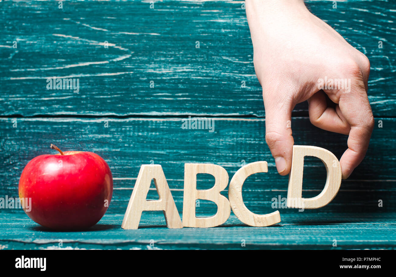 Red apple and letters of the ABCD. The hand puts the letter D to the ...