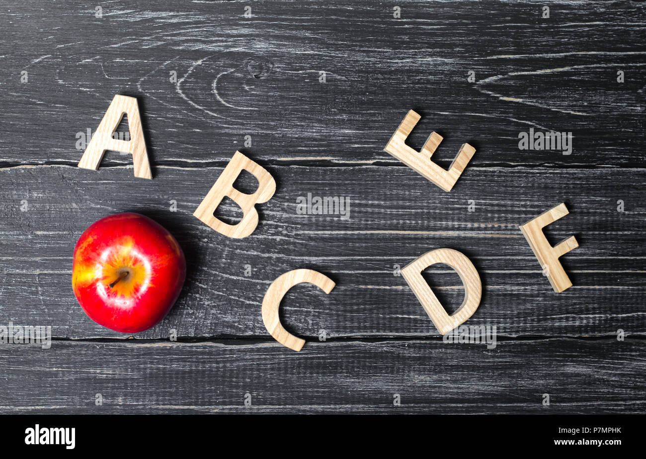 Red apple and alphabet made of wooden letters on a dark background of a ...