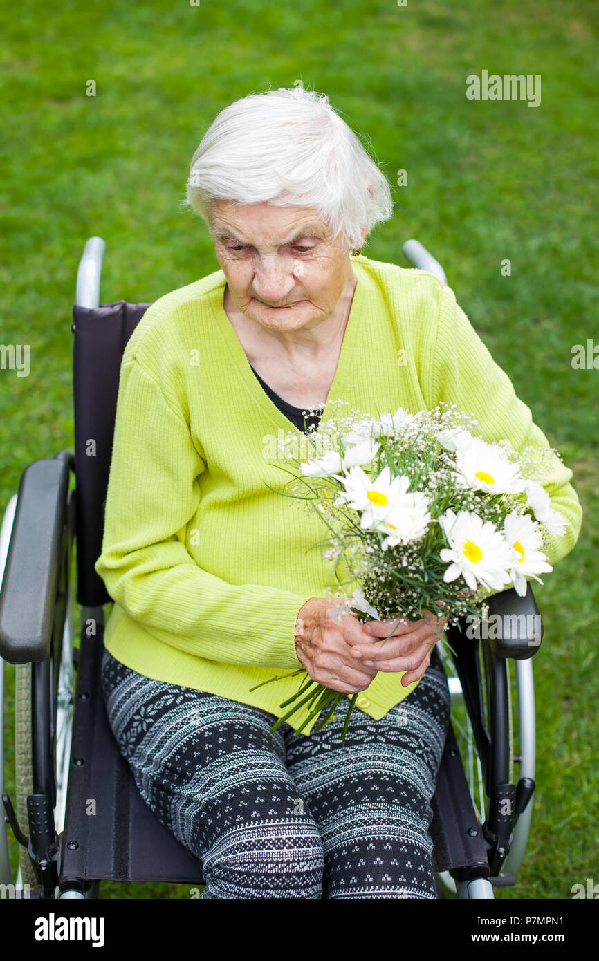 Disabled elderly woman sitting in wheelchair, receiving a flower ...