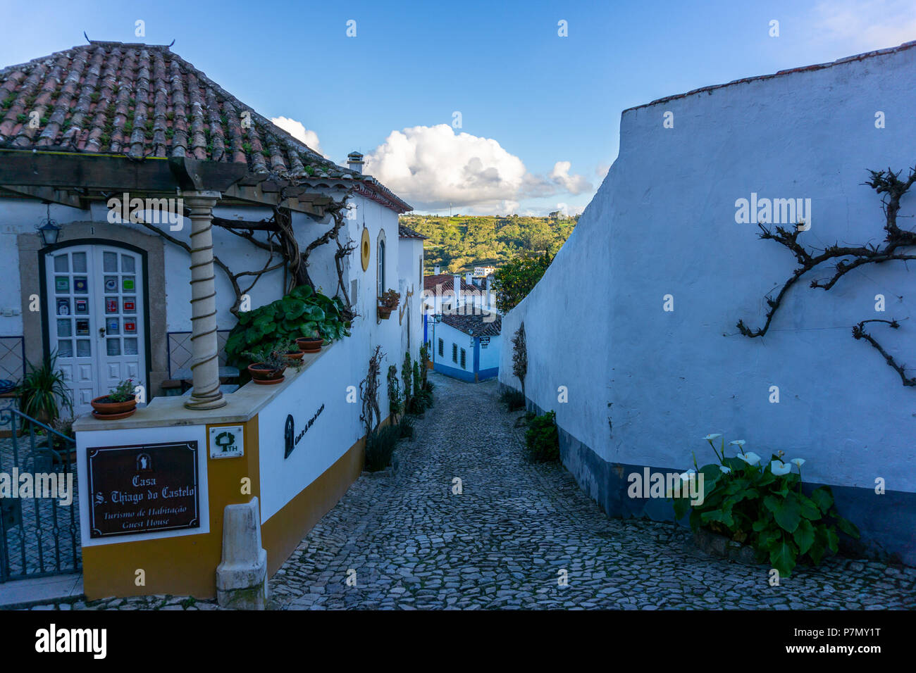 View down a narrow cobbled street with green landscape in the distance ...