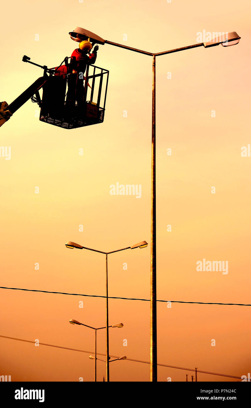 An electrical power utility worker in a bucket fixes the power line ...