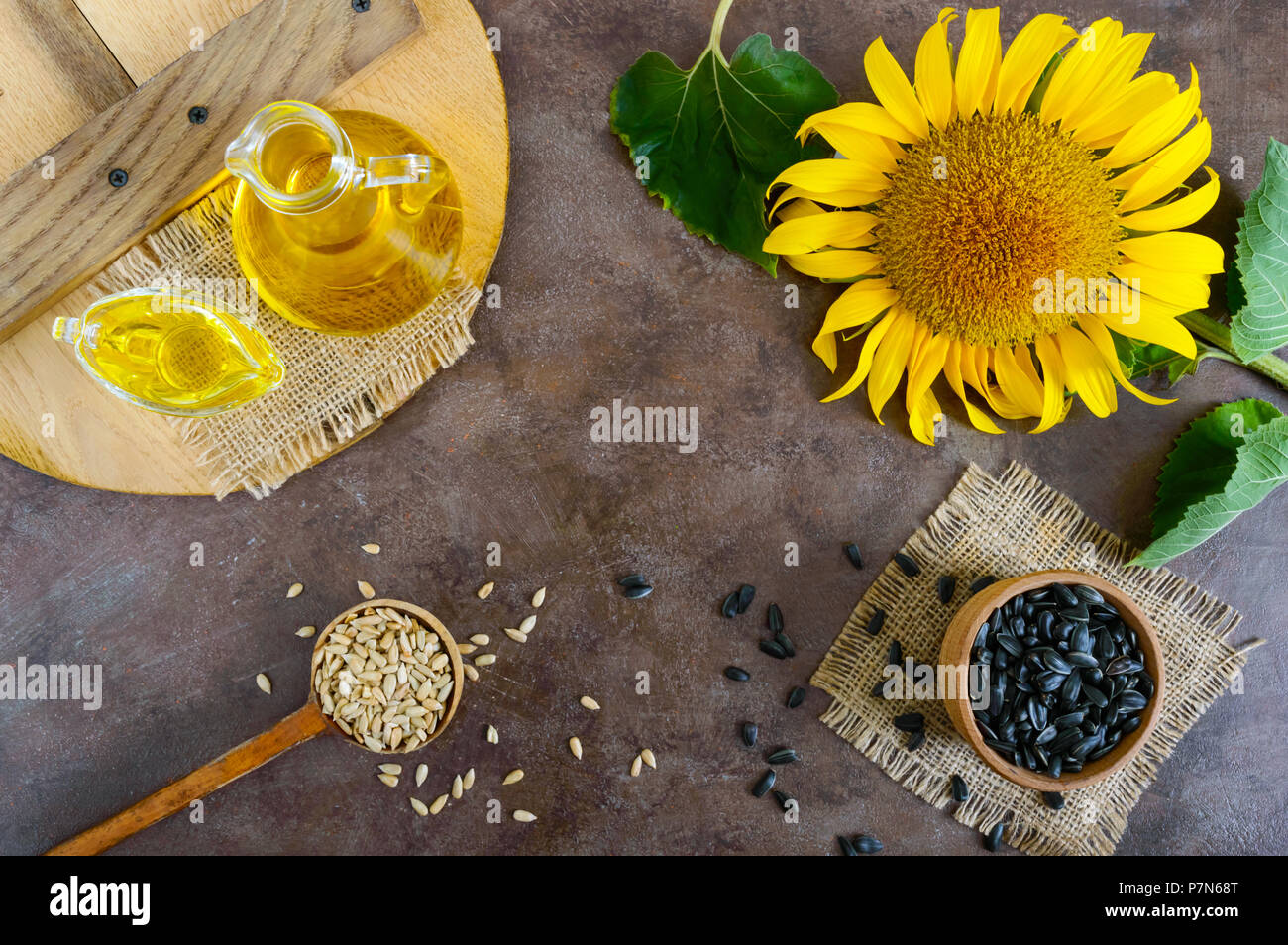A large sunflower, a bottle of oil, seeds on the table. Top view ...