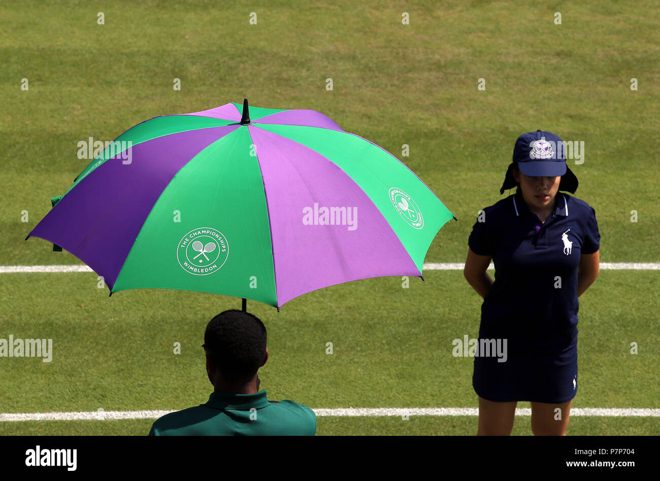 A player is sheltered from the sun with an official umbrella on day six ...