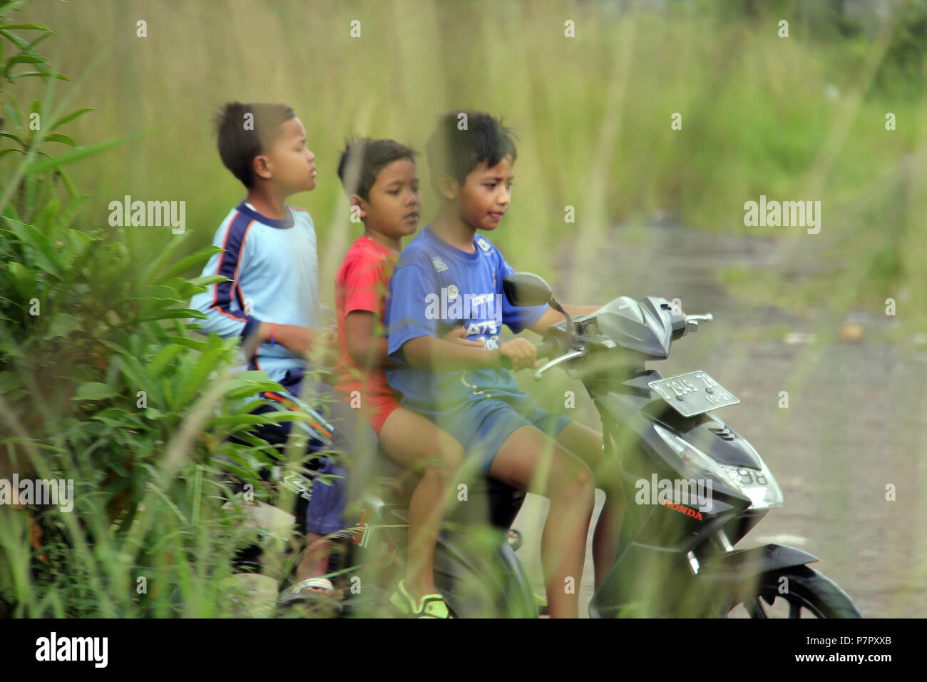 Three boys riding motorcycles in Bandung Indonesia Stock Photo - Alamy