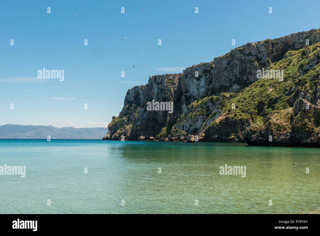 The cliff of Quemado beach with people bathing, gulls and crystal clear ...