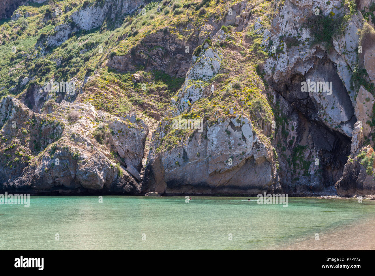 The cliff of Quemado beach with people bathing, gulls and crystal clear ...