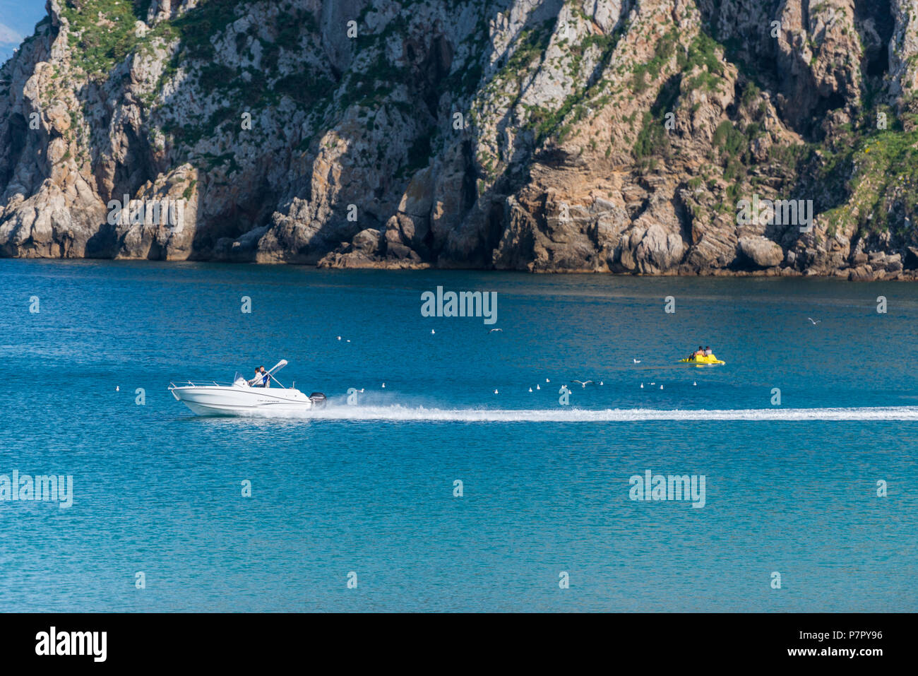 A speedboat passes by the beach of El Quemado with the cliff in the ...