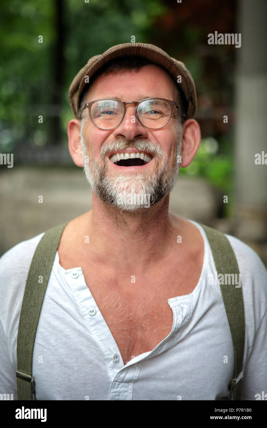 portrait of handsome laughing bearded man with hat and eyeglasses in ...