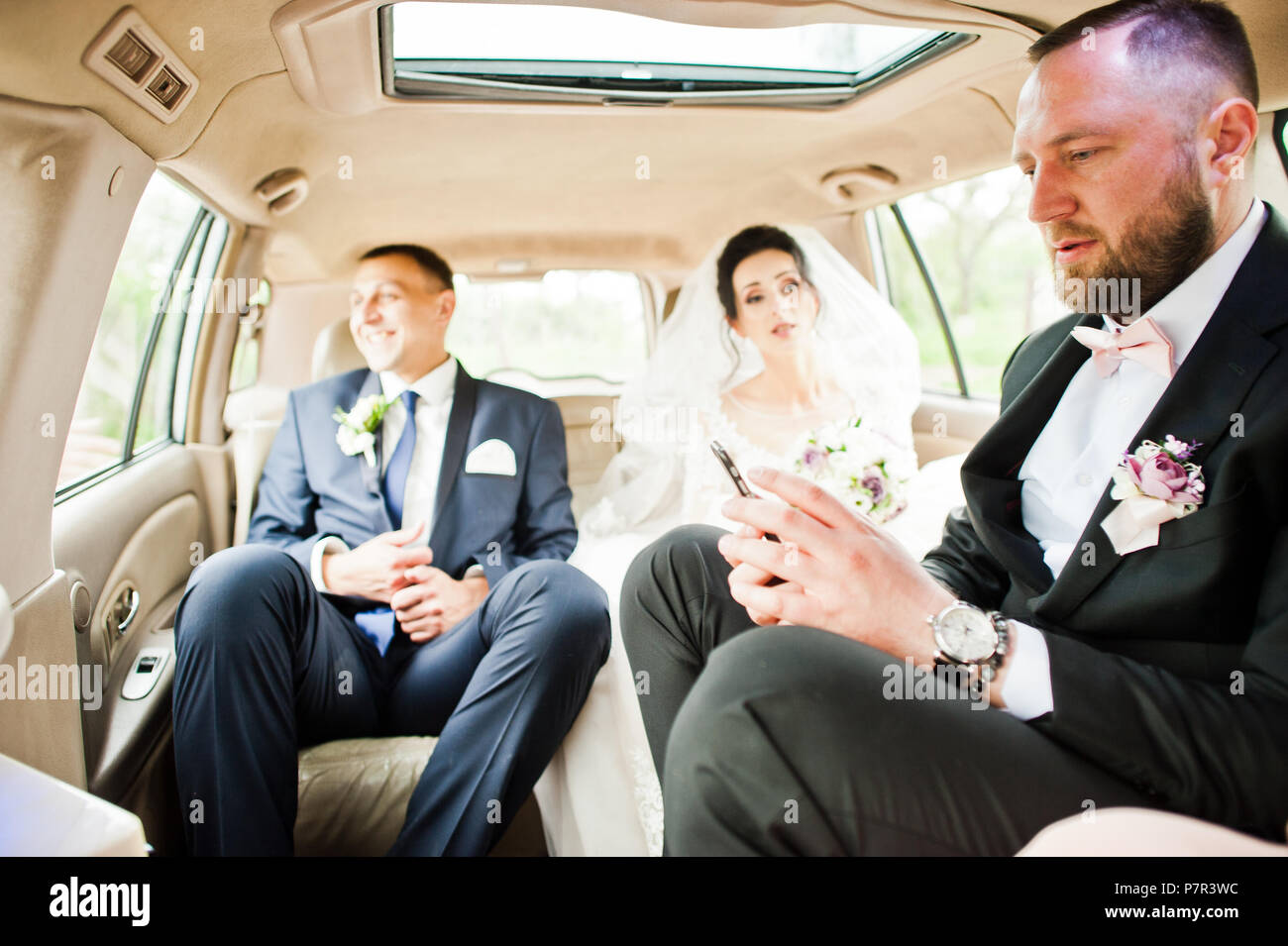 Fabulous wedding couple and groomsman sitting in the car before the ...