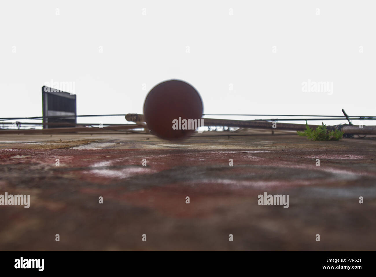 Low angle view of a plastic pipe on an eroded red and black wall and a ...