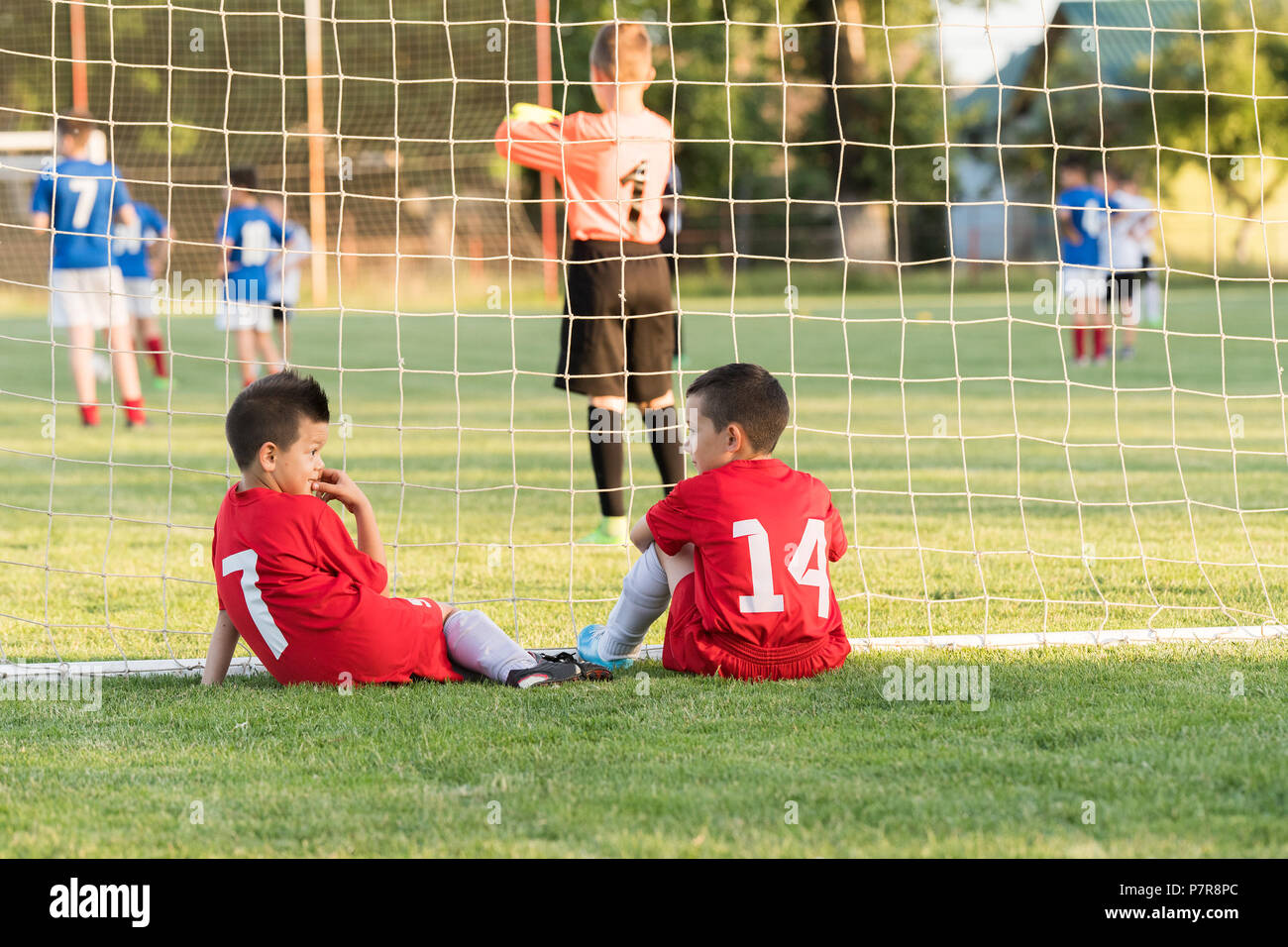 Kids soccer players sitting in out behind goal watching football match ...