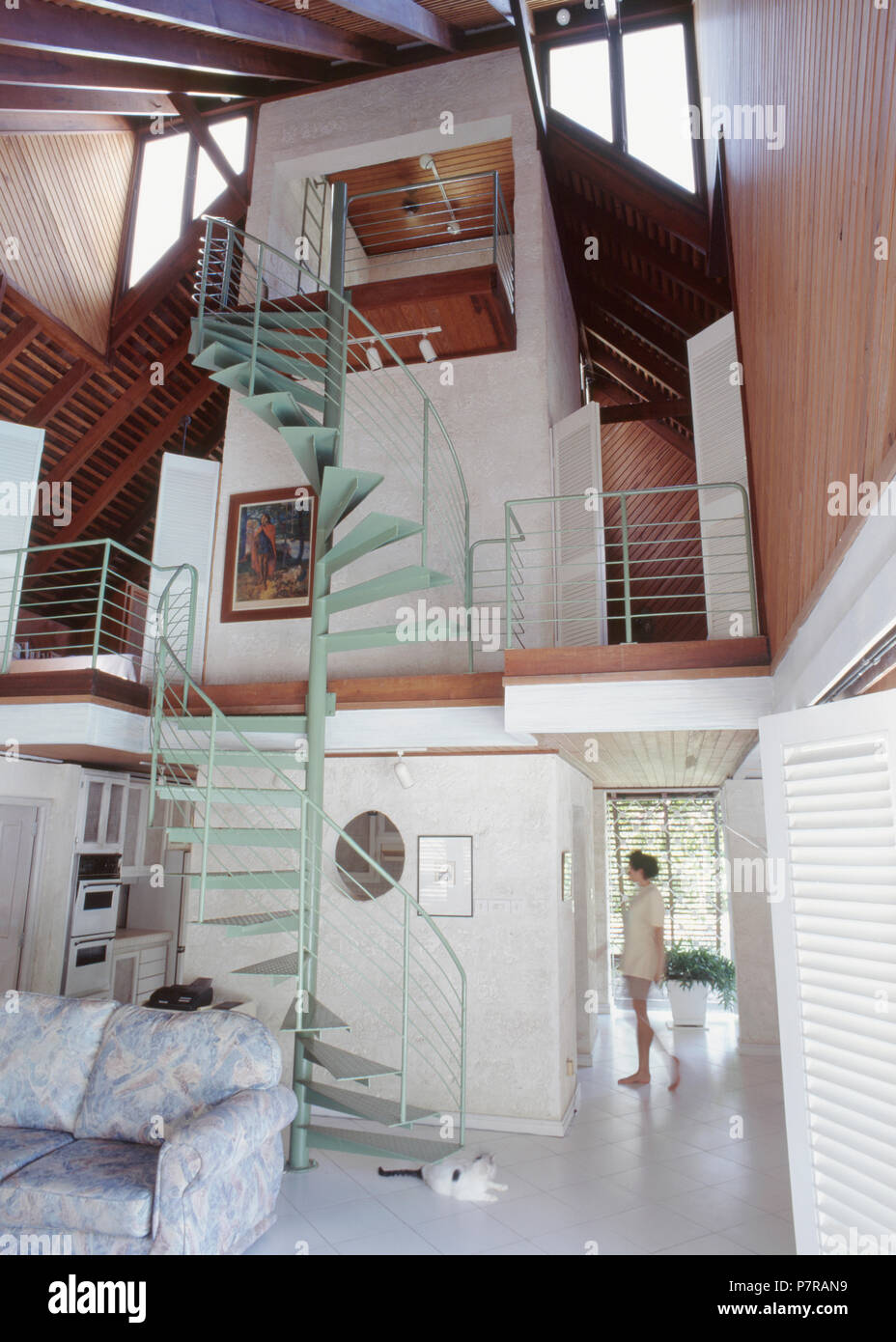 Pastel green metal spiral staircase in openplan triple height hall with ...