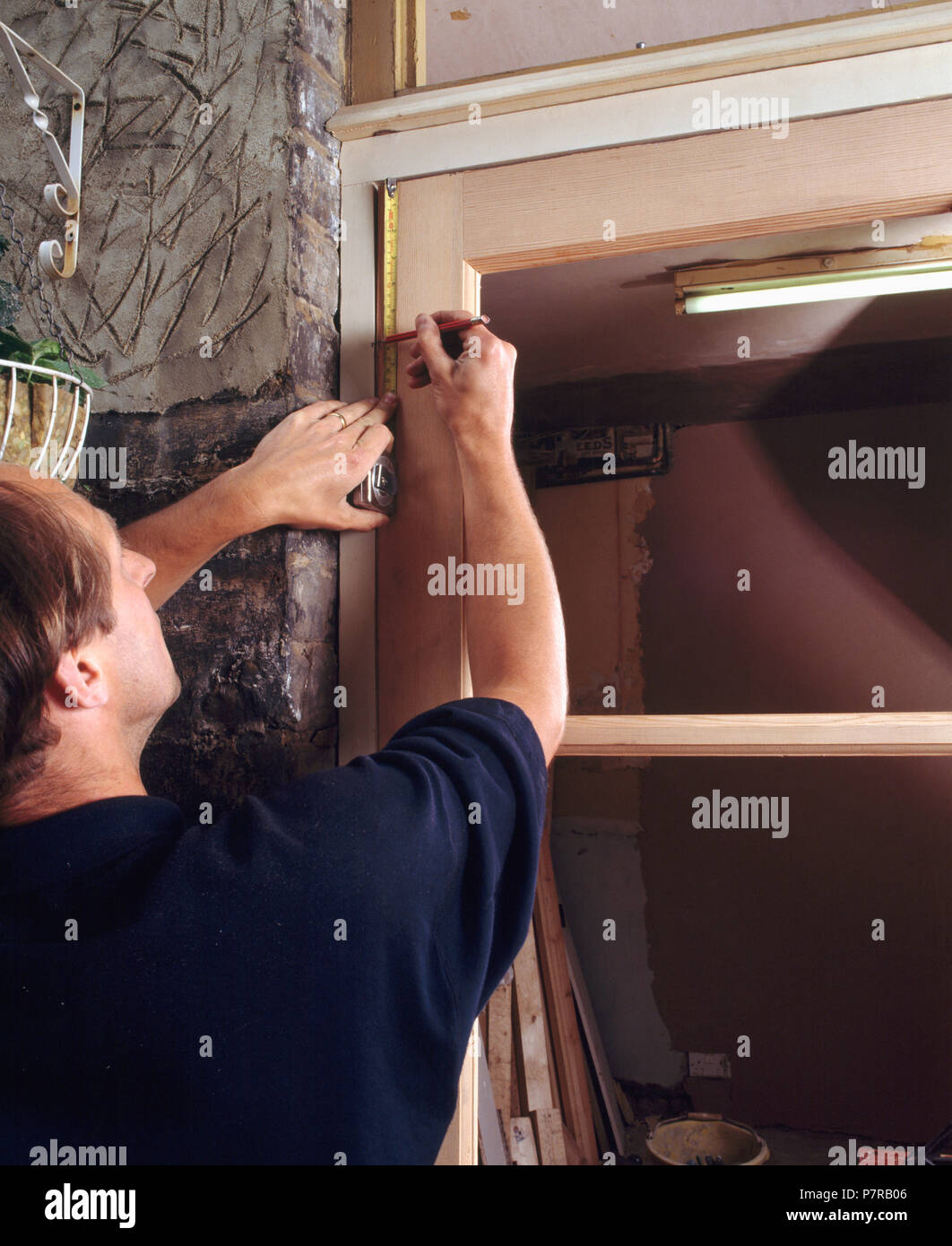 Man using tape measure on wooden door frame FOR EDITORIAL USE ONLY ...