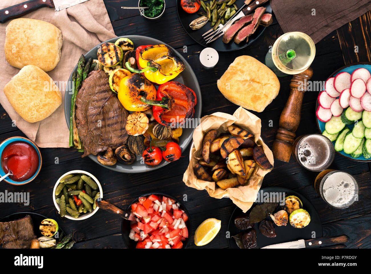 Meat and vegetables cooked on a grill on a dark wooden table with wine ...