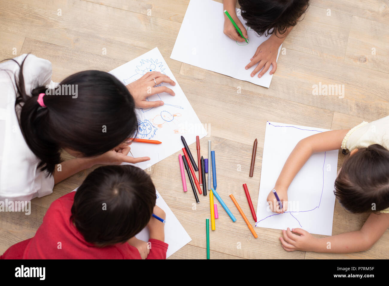 Group of preschool student and teacher drawing on paper in art class ...