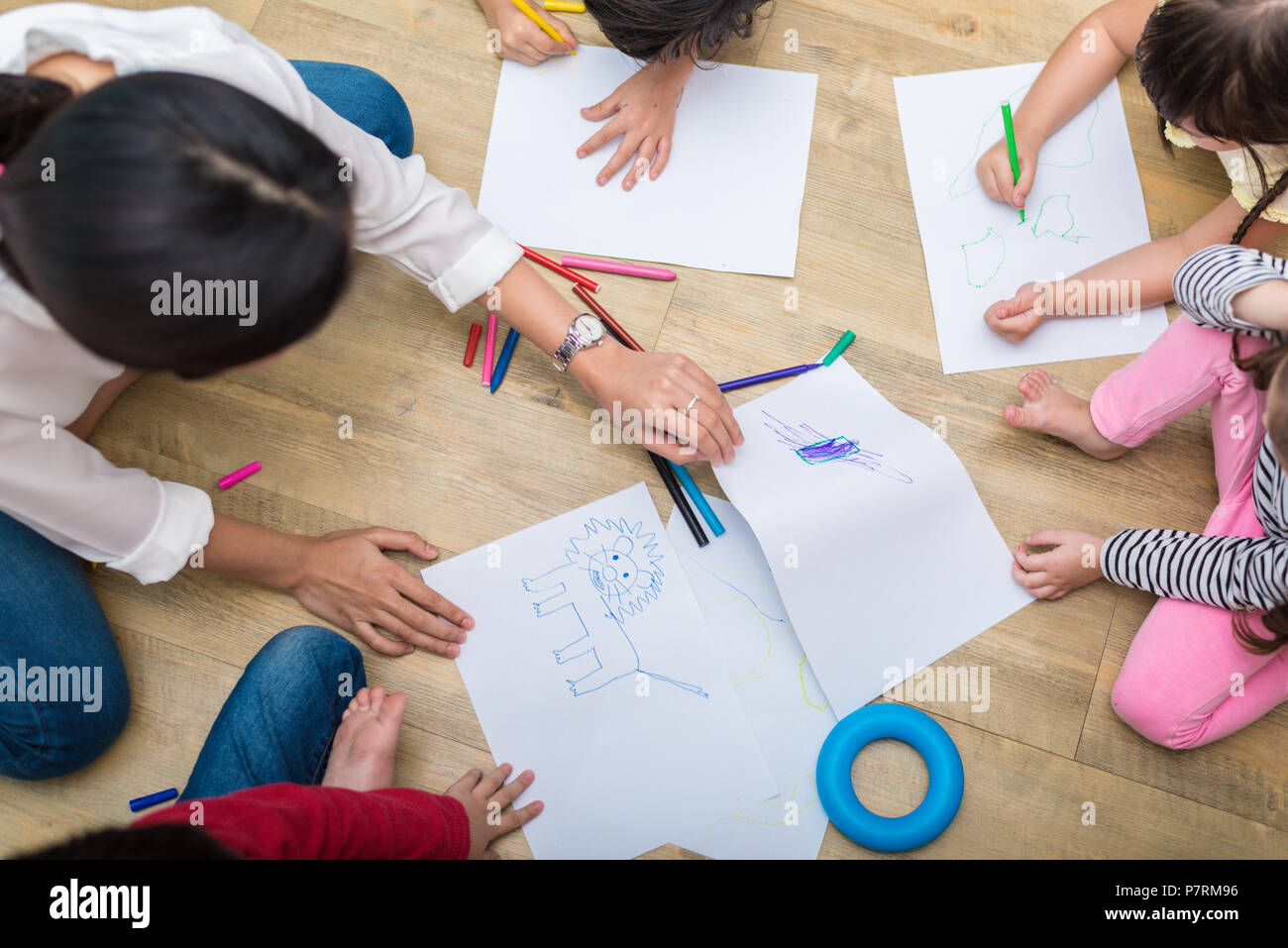 Group of preschool student and teacher drawing on paper in art class ...