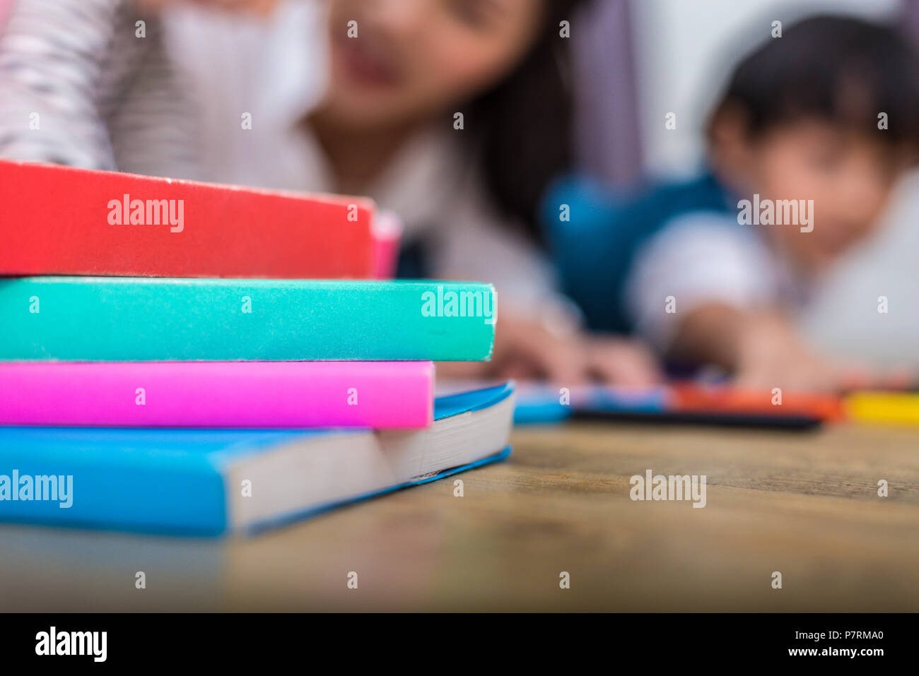 Close up of books on floor with mom and kids background. Back to school ...