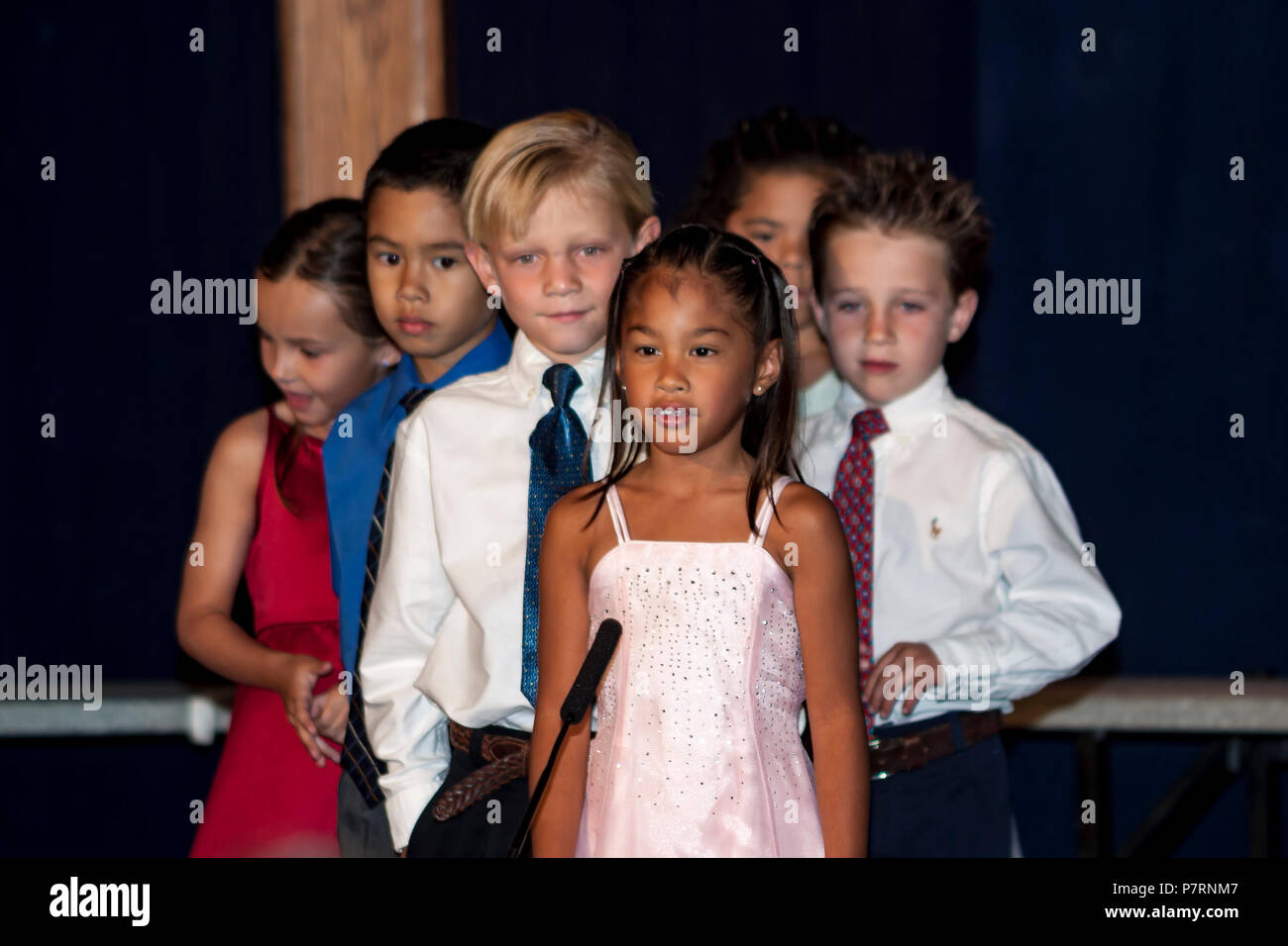 Kindergarten age kids line up to take a part in reciting on stage ...