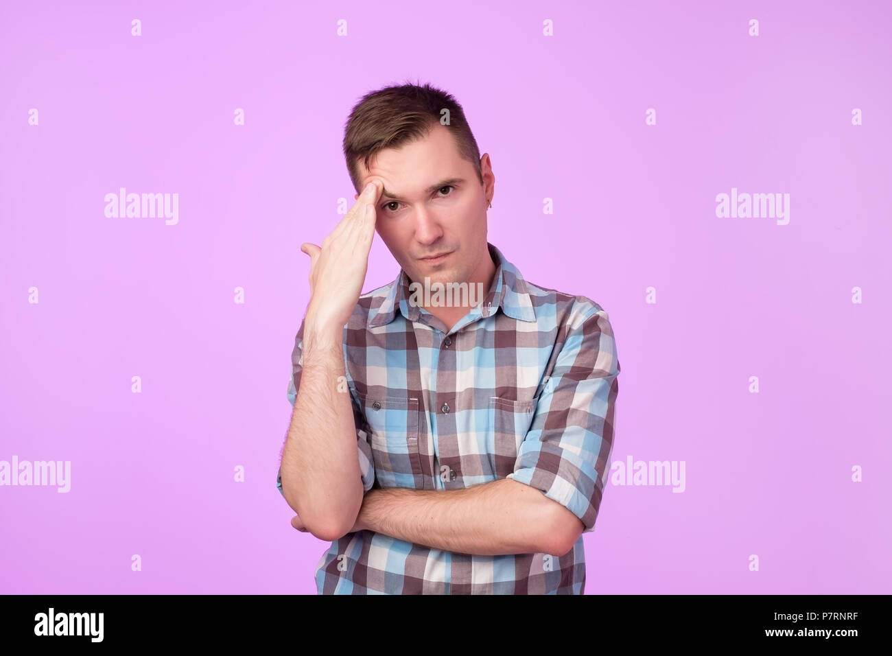 young man thinking against pink background. He is not sure in future ...