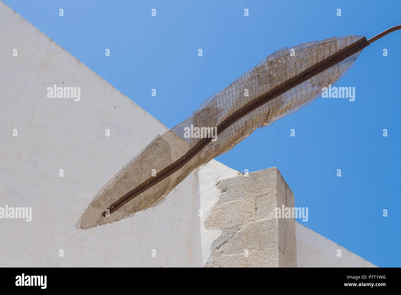 Steel detail of a statue in a form of a leaf. Part of a building with a ...