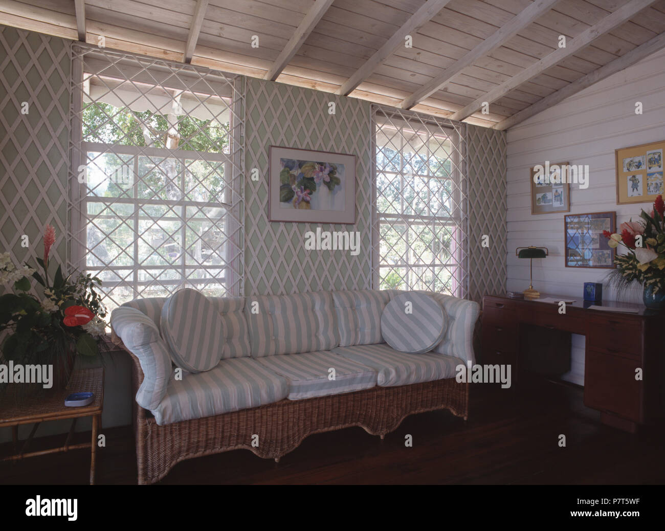 Striped cushions on wicker sofa below windows with security grille in ...