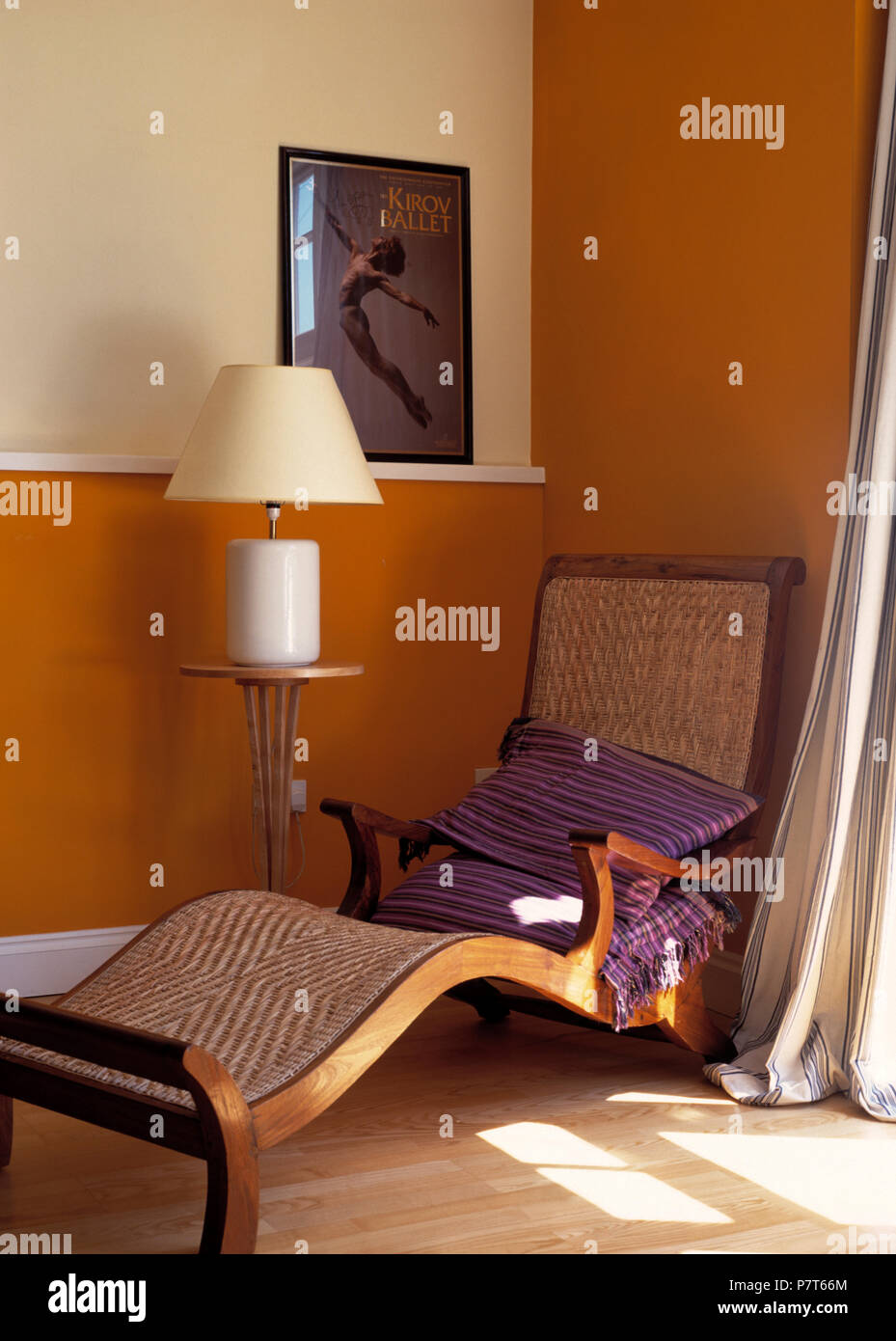 Folded rug on cane seated chaiselongue in orange room with white lamp ...